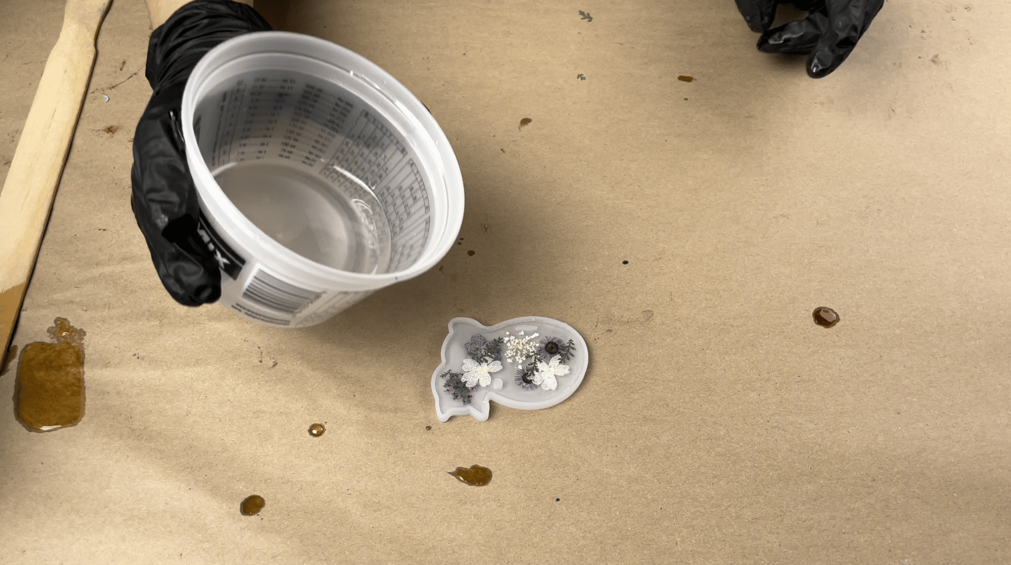 Cup-of-table-top-resin-being-poured-in-a-cat-mold-with-flowers - Resin ...